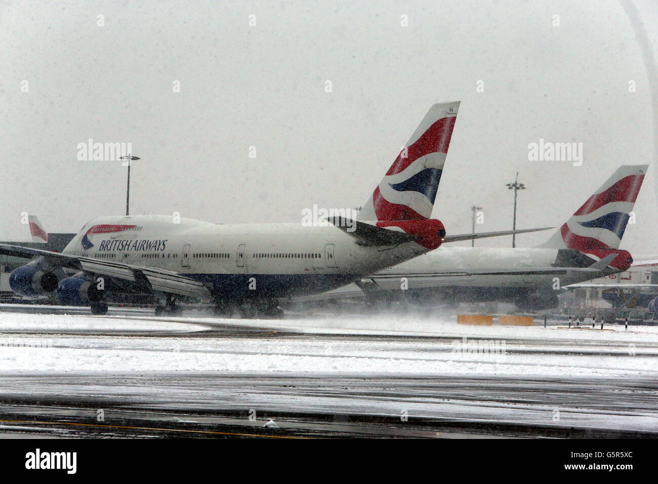 Planes standing in the snow at heathrow airport hi-res stock ...