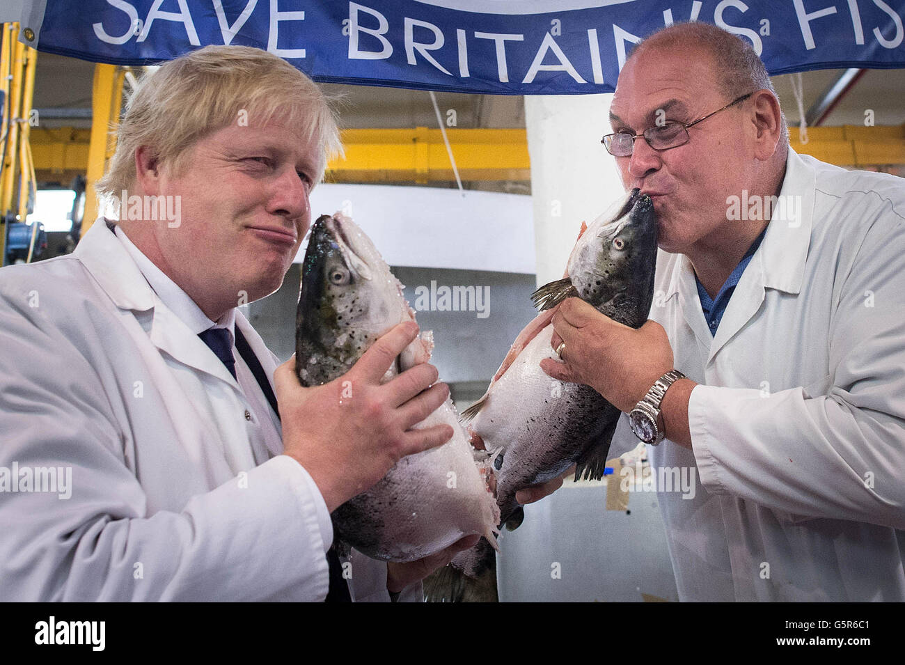 Boris Johnson (left) kisses a wild salmon as he is shown around ...