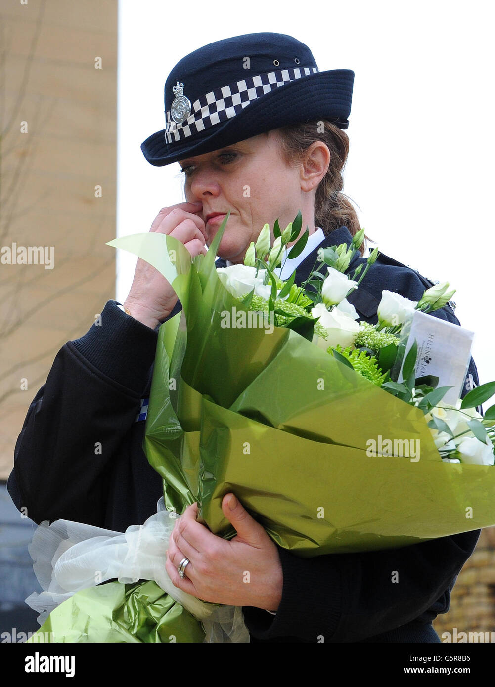 A police officer holds flowers during a press conference outside ...