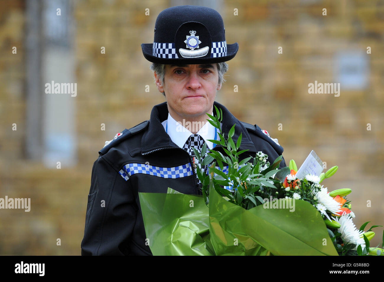 A police officer holds flowers during a press conference outside ...