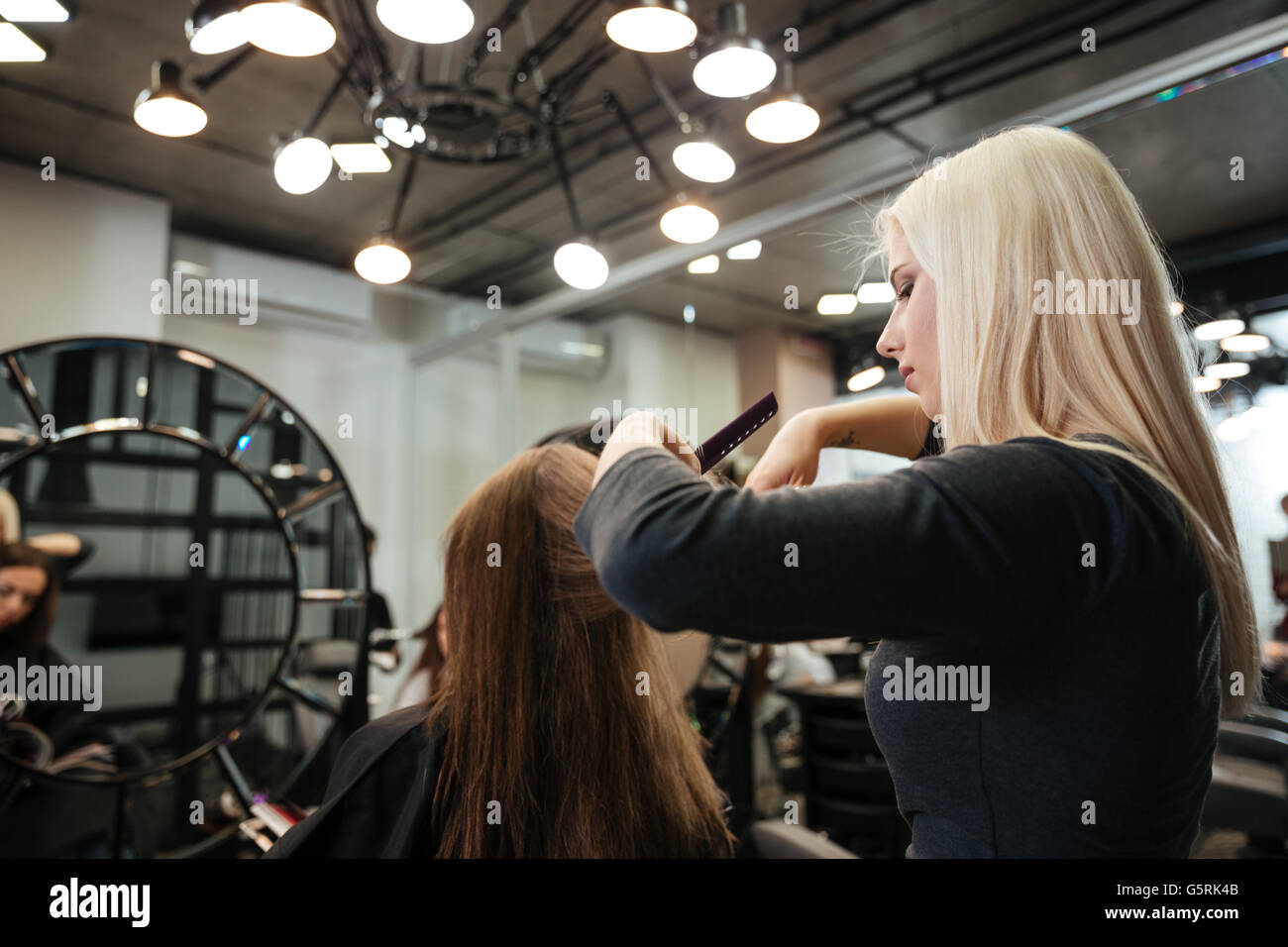 Happy young woman getting new haircut by female hairdresser at beauty ...