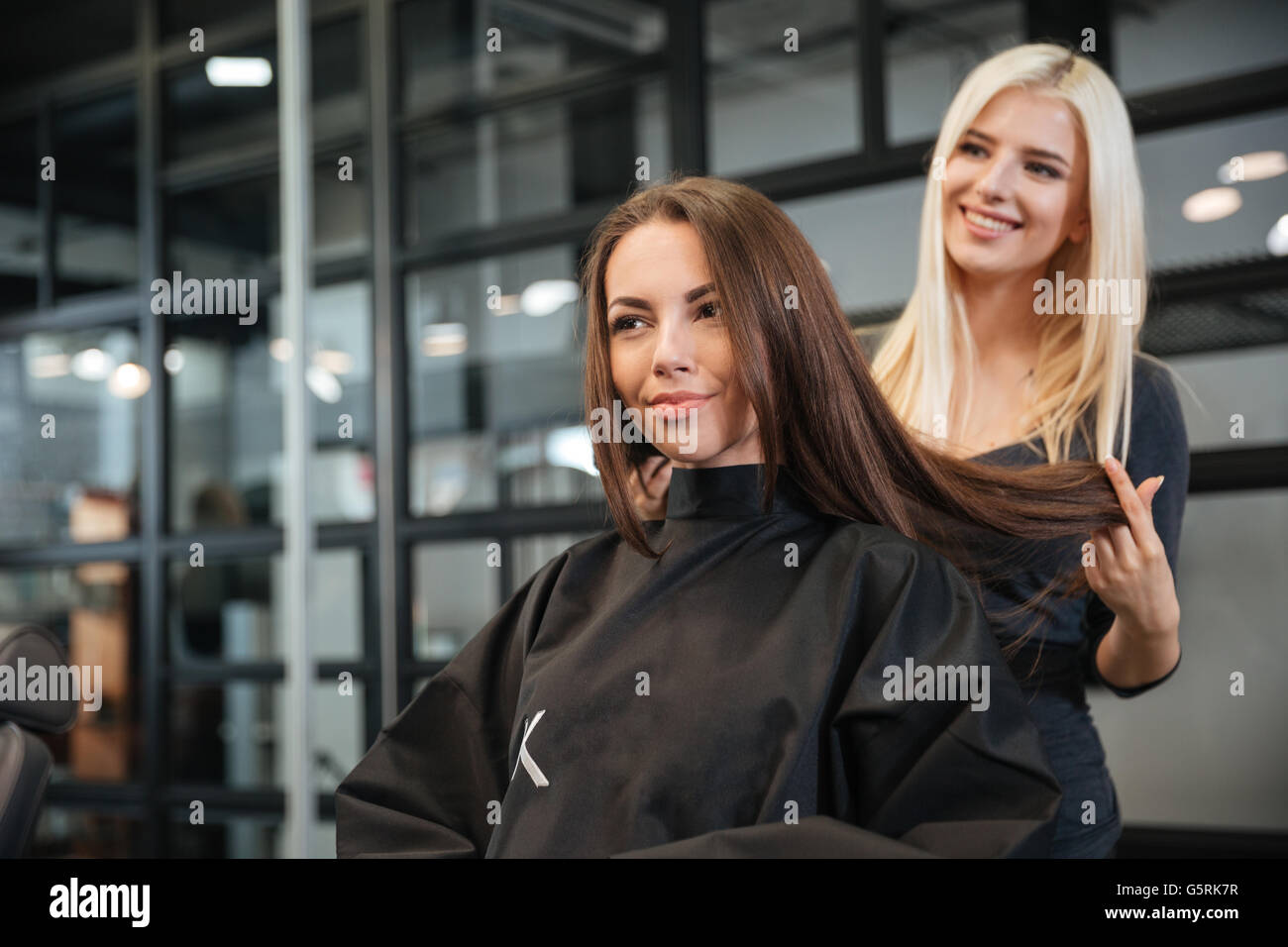 Young hairdresser giving a new haircut to female customer at parlor ...
