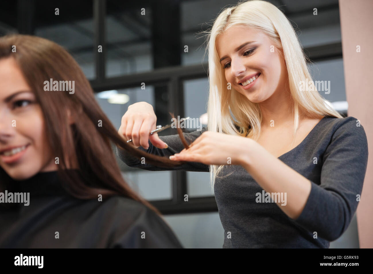 Happy young woman getting new haircut by female hairdresser at beauty ...