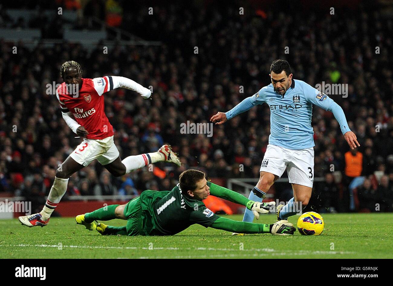 Manchester City's Carlos Tevez (right) takes the ball around Arsenal's ...