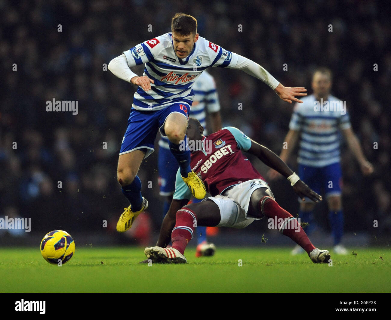 QPR's Jamie Mackie (top) avoids a challenge from West Ham's Mohamed ...