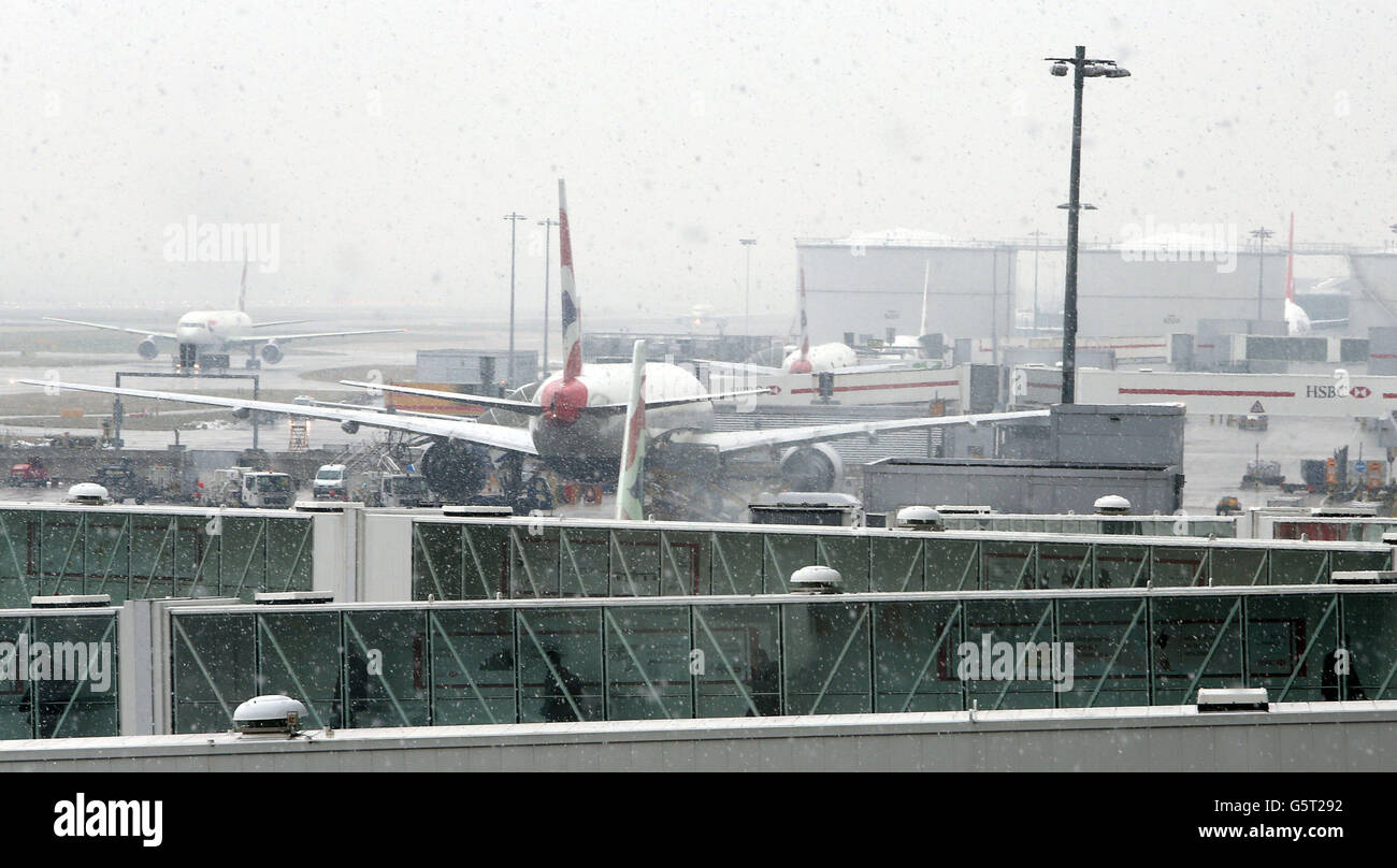 Passengers board planes as a snow shower falls at Heathrow Airport as ...