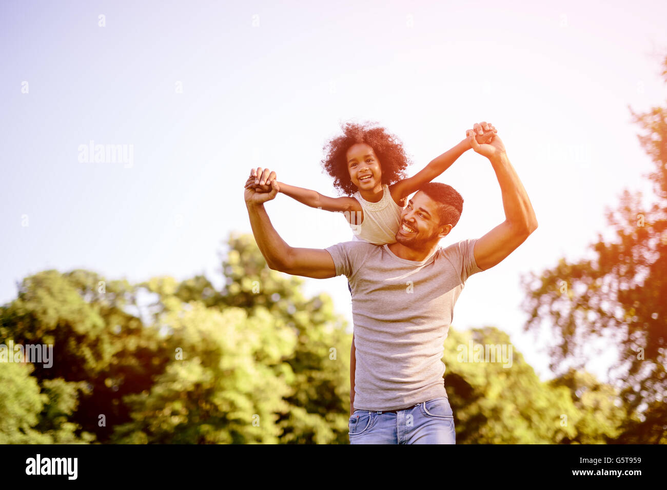 Child flying on father shoulders while held piggyback Stock Photo - Alamy