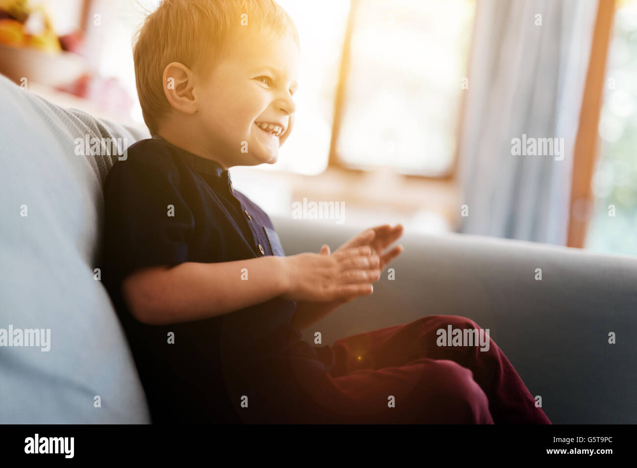 Happy boy sitting on sofa in living room Stock Photo - Alamy