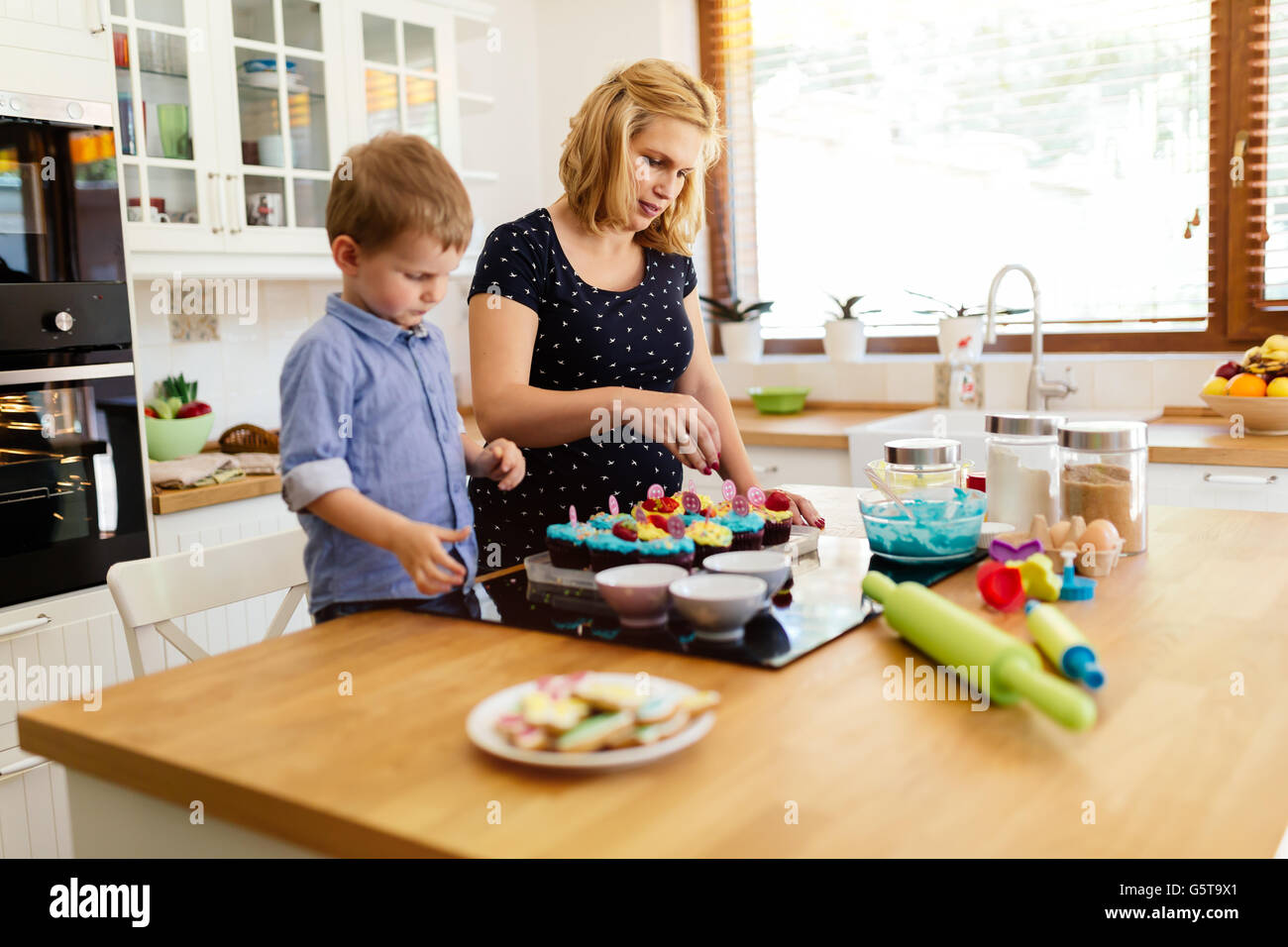 Smart cute child helping mother in kitchen preparing cookies Stock ...