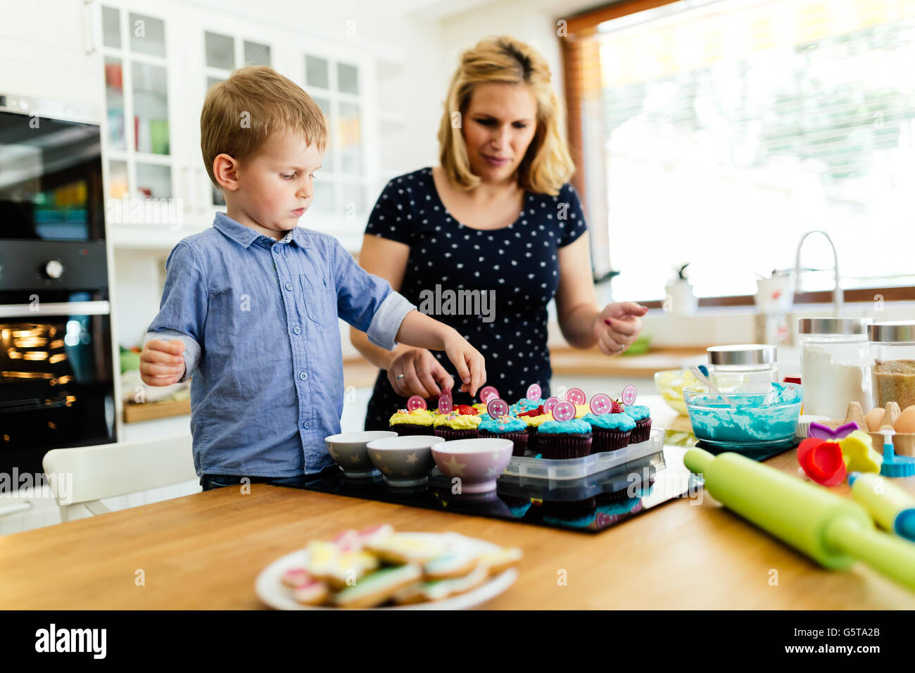 Smart cute child helping mother in kitchen preparing cookies Stock ...