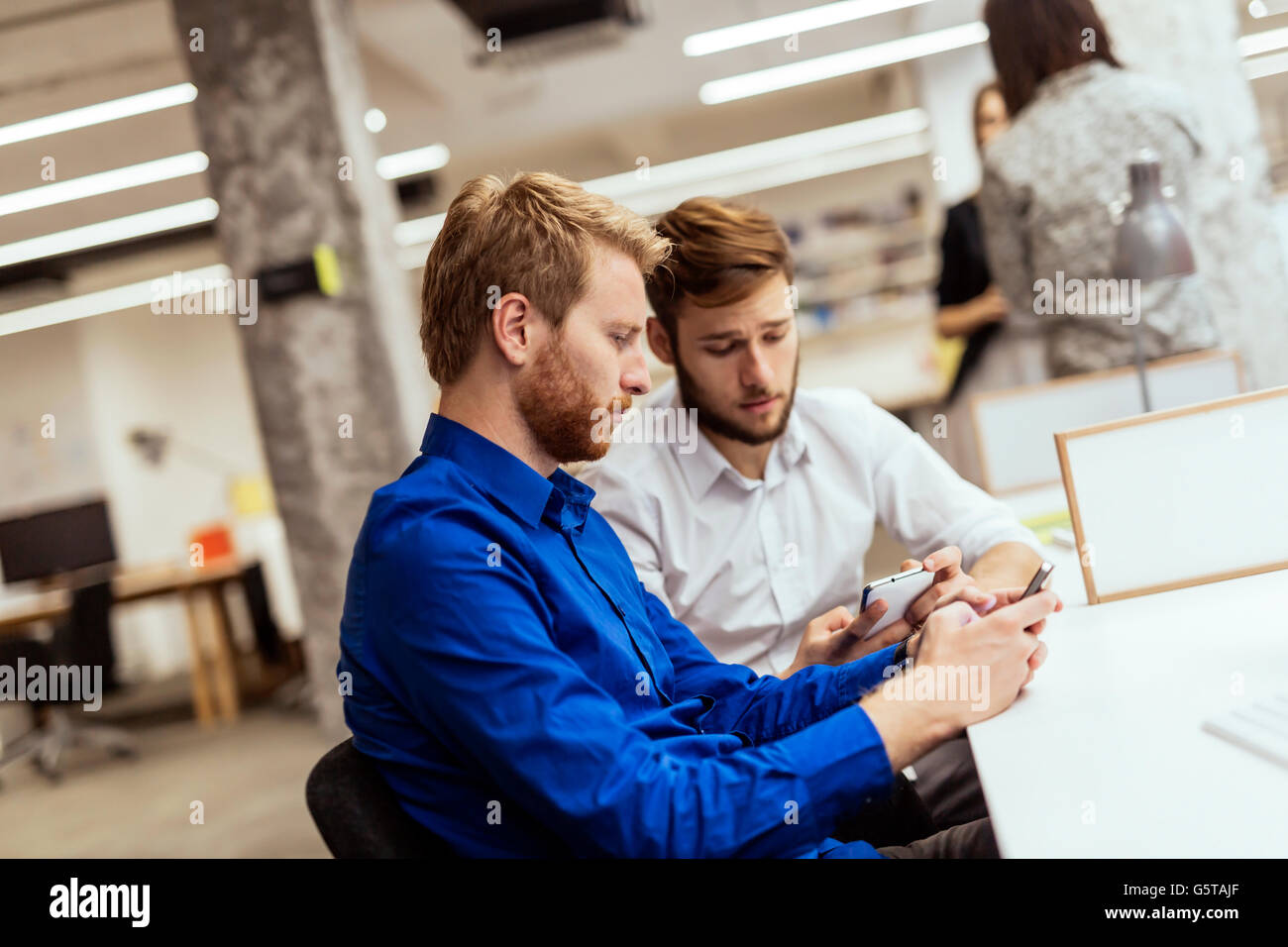 Handsome businessmen using phones and calling partners while sitting at ...