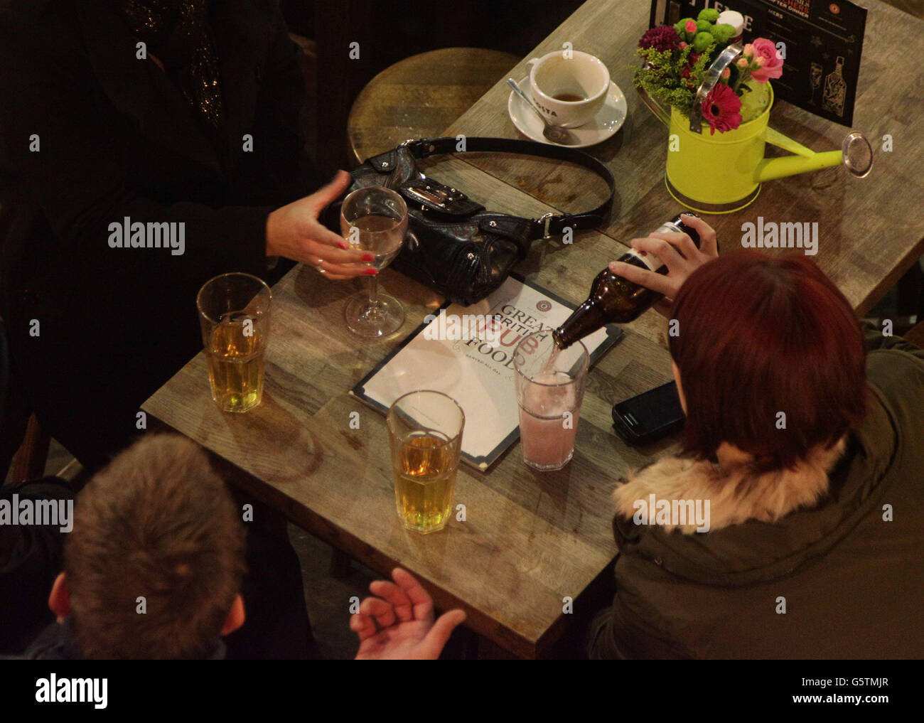 People sat around a table drinking wine and lager in a pub in Covent ...