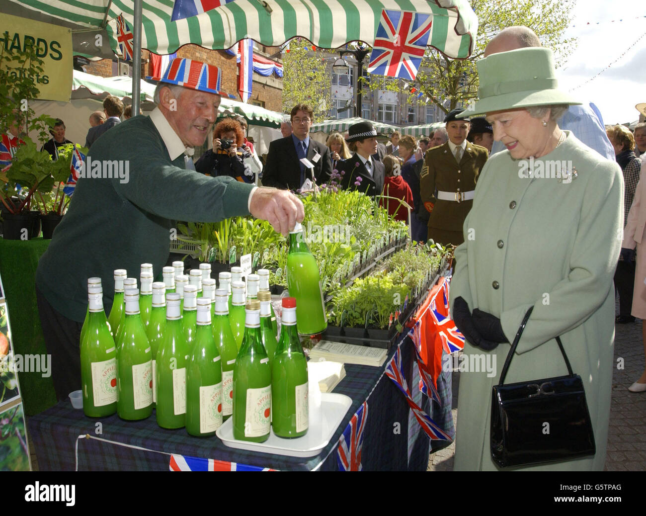 Britain's Queen Elizabeth II looks at some local apple juice at a ...