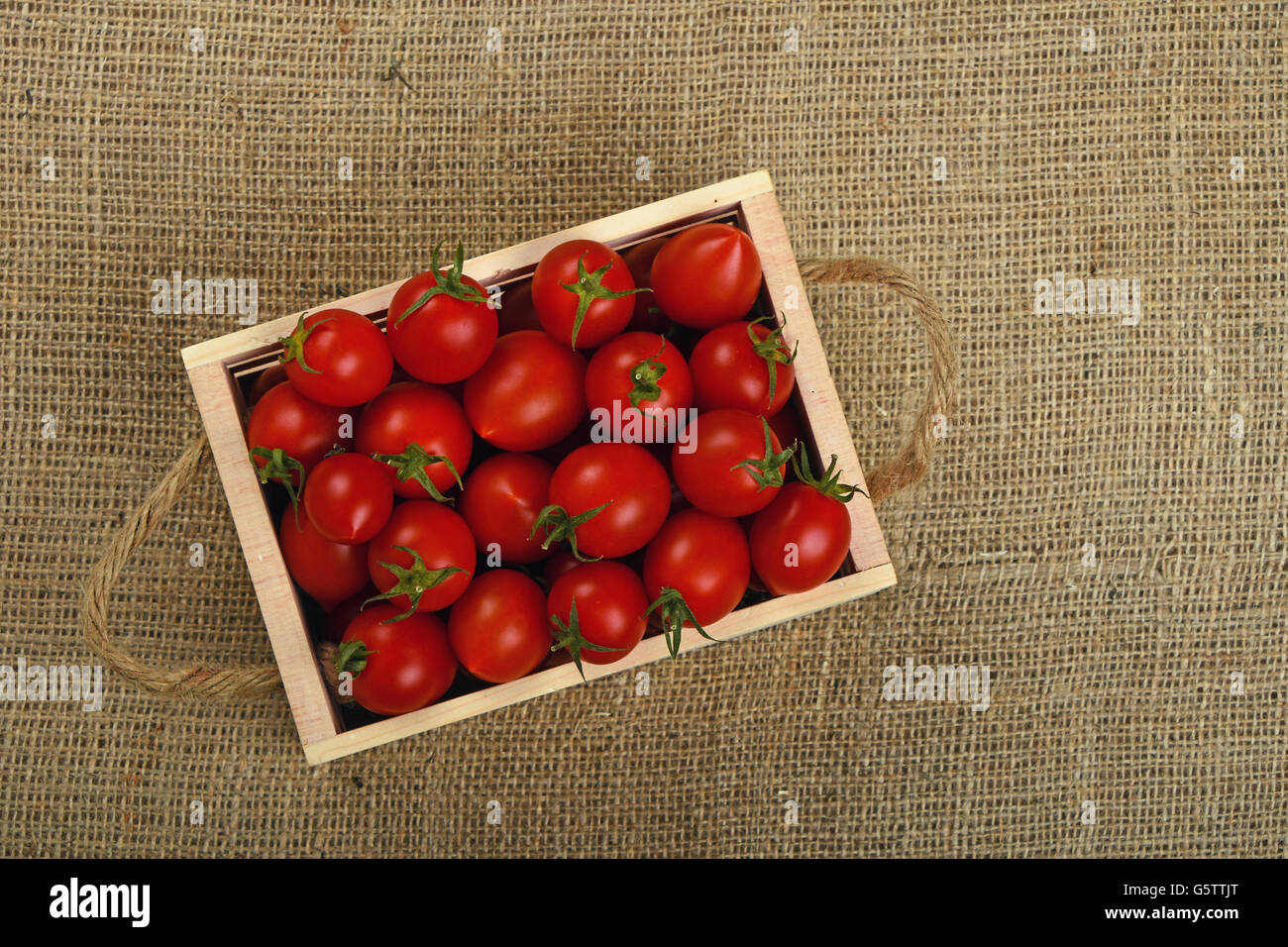 Red ripe fresh cherry tomatoes in small wooden box with twine jute ...