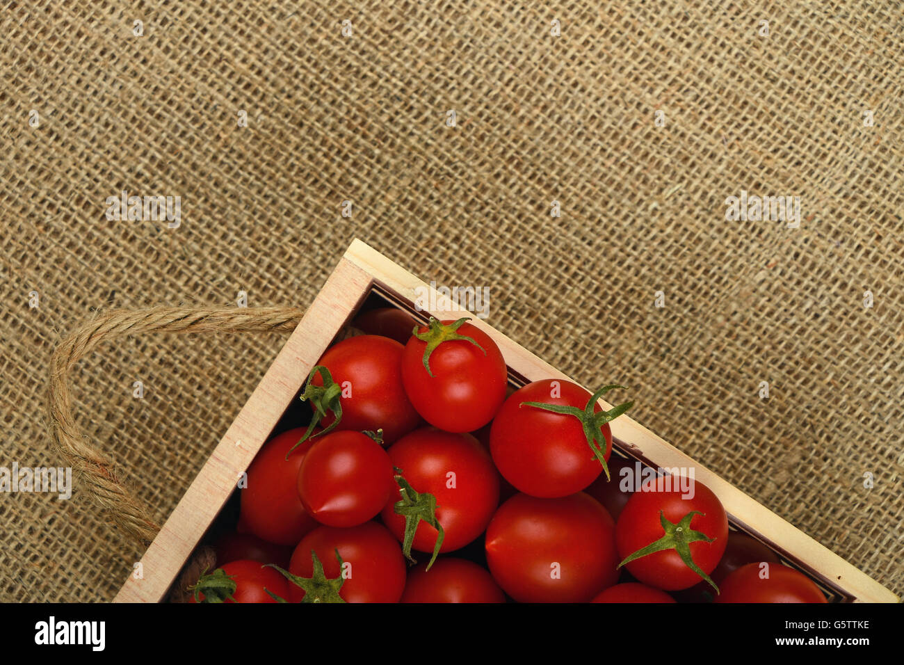 Red ripe fresh cherry tomatoes in small wooden box with twine jute ...