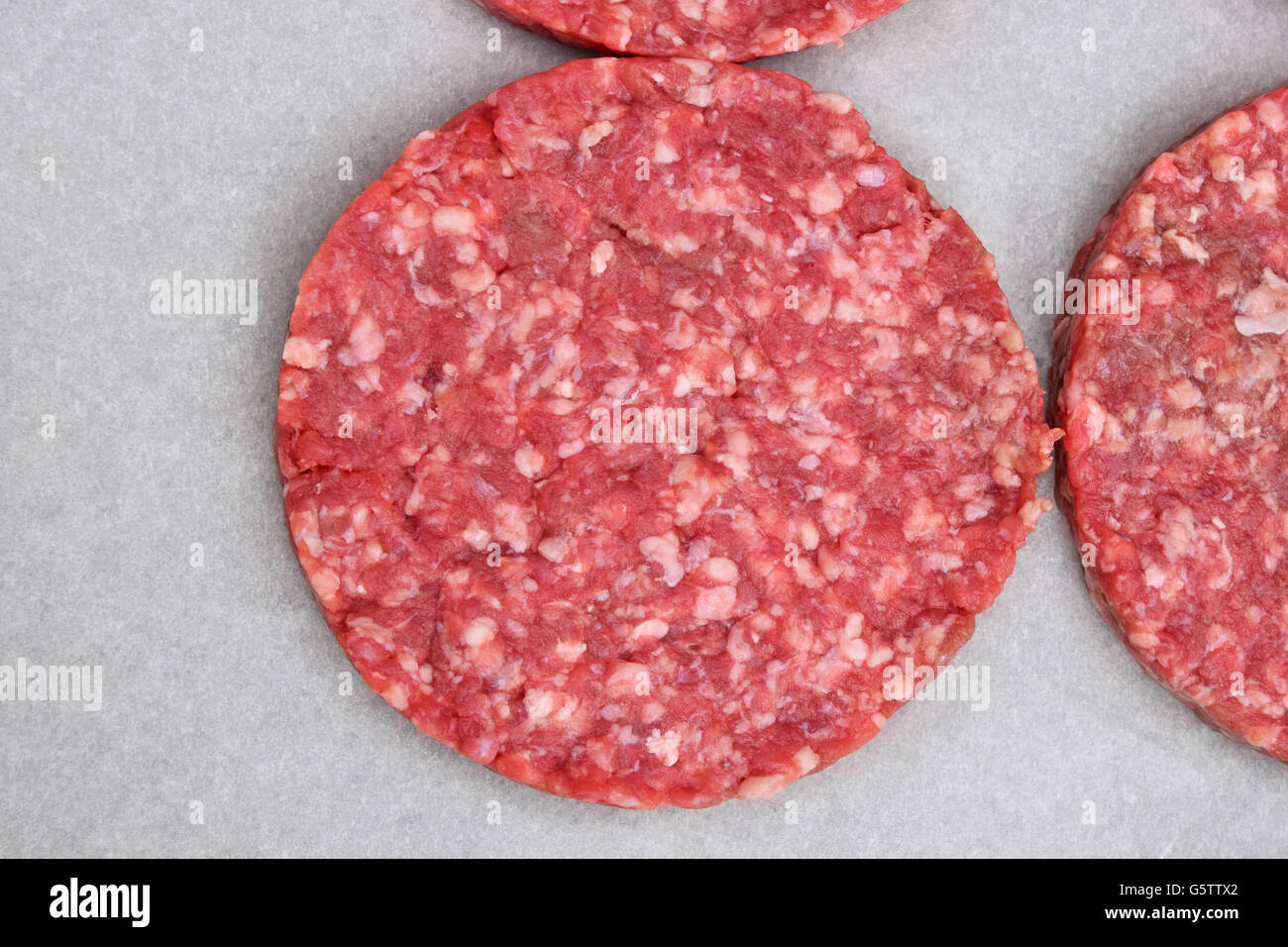 Raw red meat burgers for hamburgers of minced ground beef or pork on ...