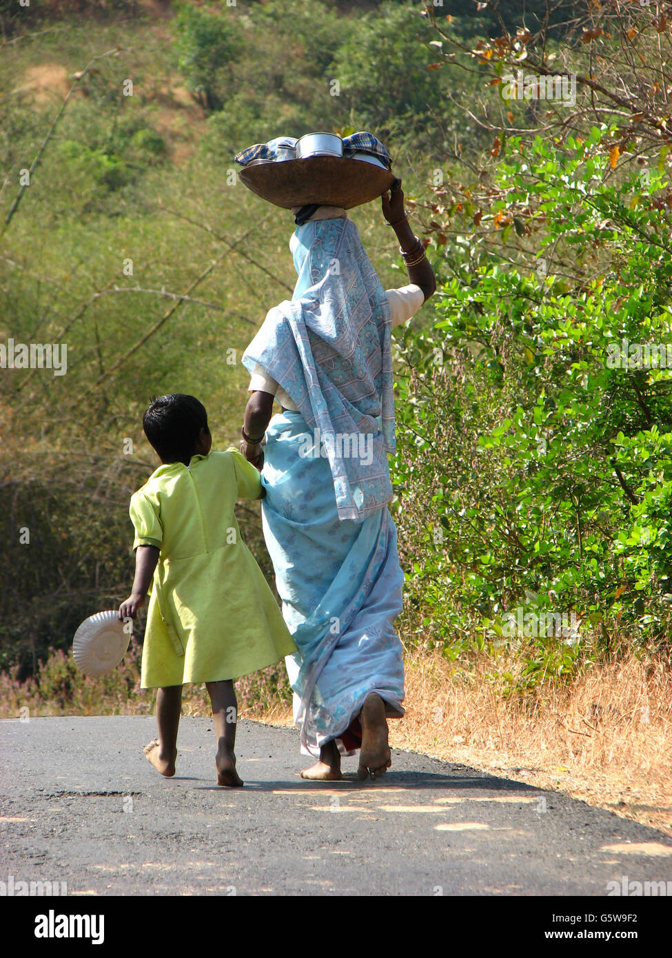 A poor Indian woman and her daughter walking home barefeet to their ...