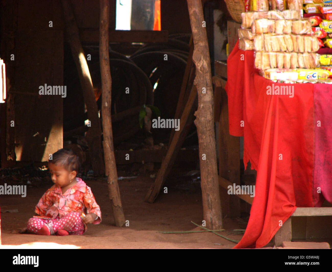 A poor toddler sitting on the outside of her hut home Stock Photo - Alamy