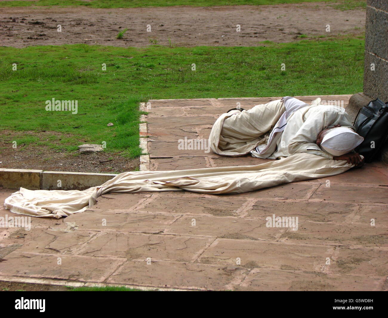 A poor pilgrim sleeping behind the temple floor in India Stock Photo ...