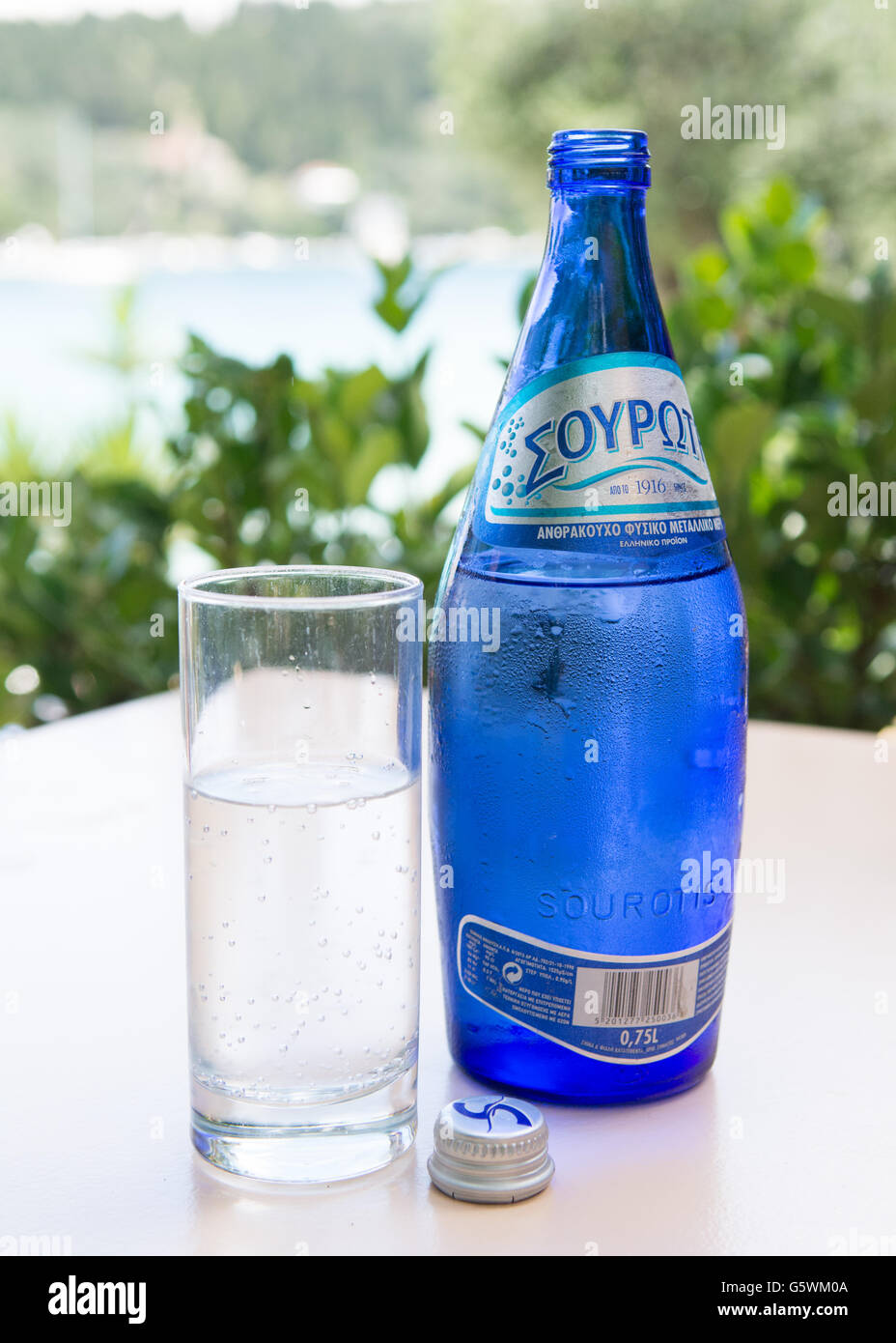 chilled bottle of water on taverna table on greek island with sea in ...