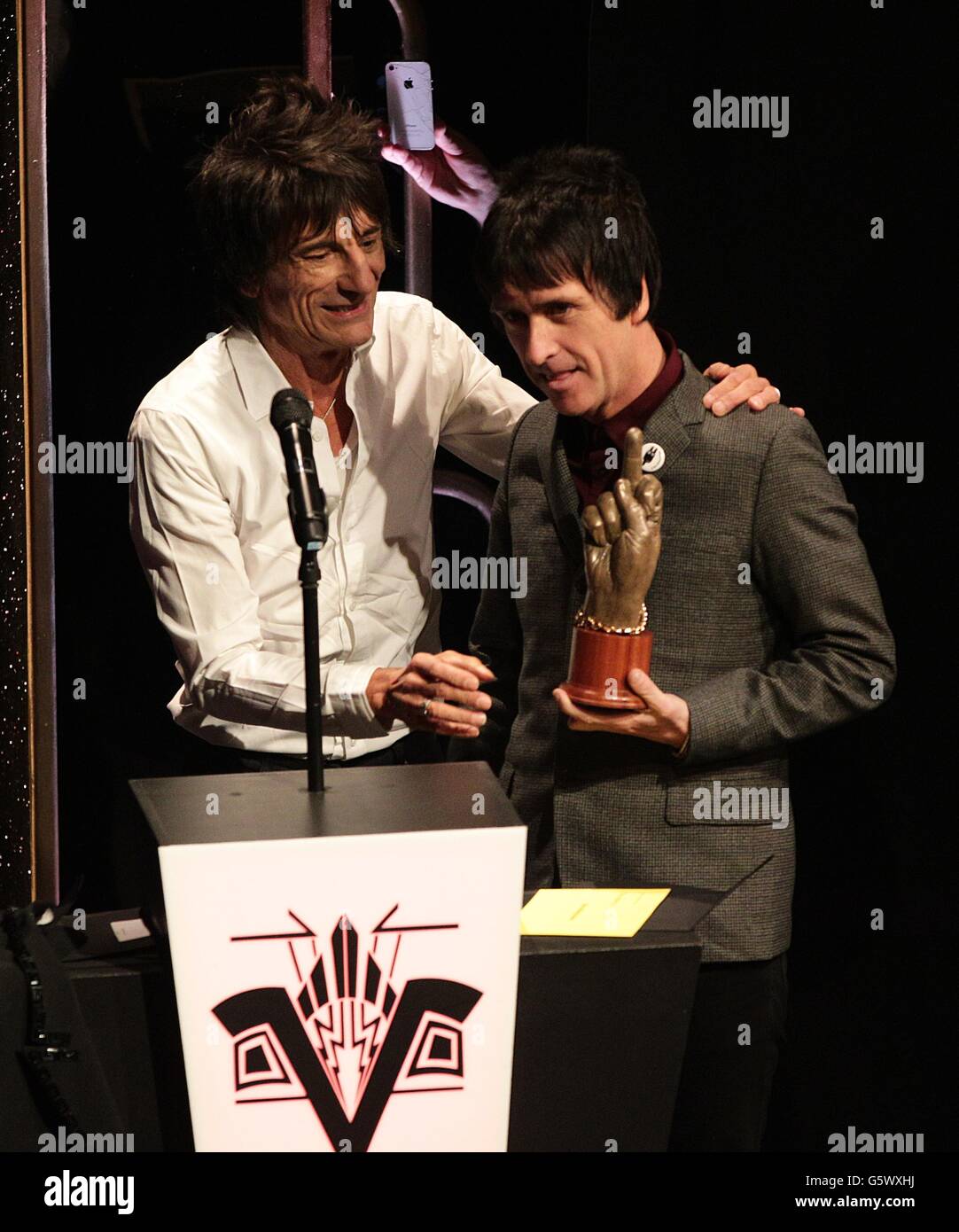 Johnny Marr (right) collects the Godlike Genius Award on stage from ...