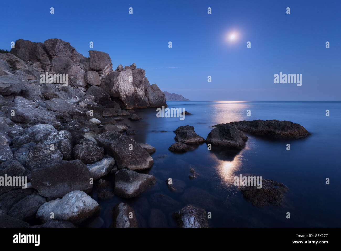 Colorful night landscape with full moon, lunar path and rocks in summer ...