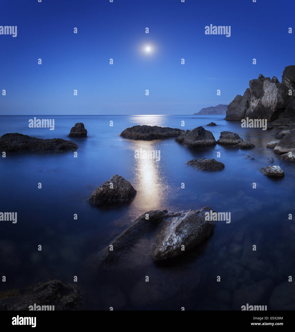 Colorful night landscape with full moon, lunar path and rocks in summer ...