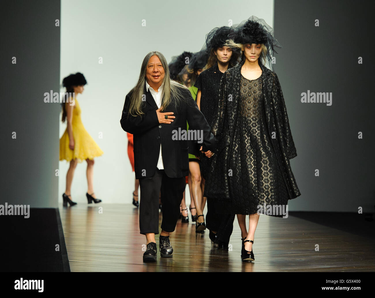 Designer John Rocha appears with models at the end of his catwalk show ...