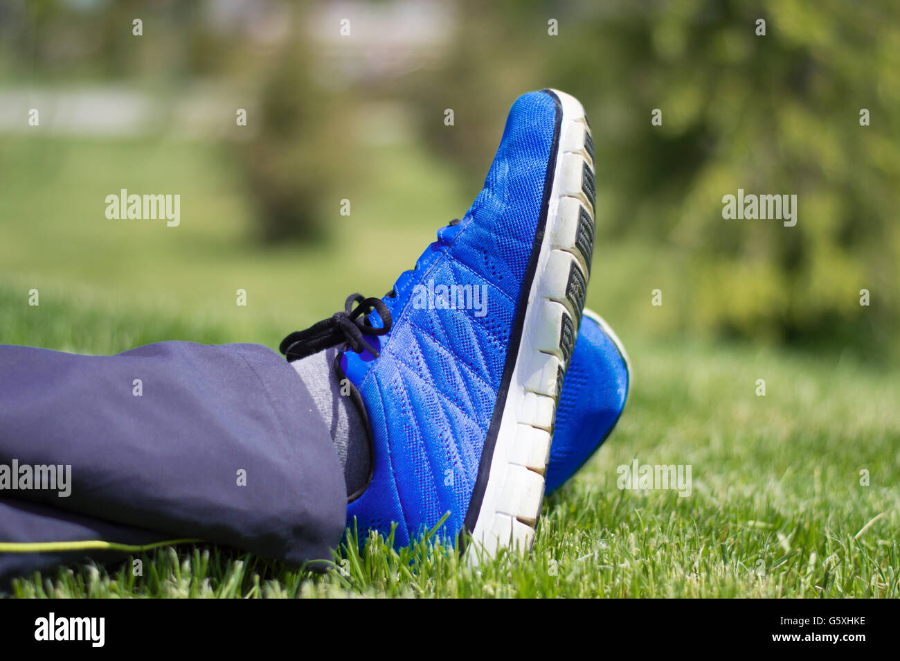 Young man with blue shoe lying on grass Stock Photo - Alamy