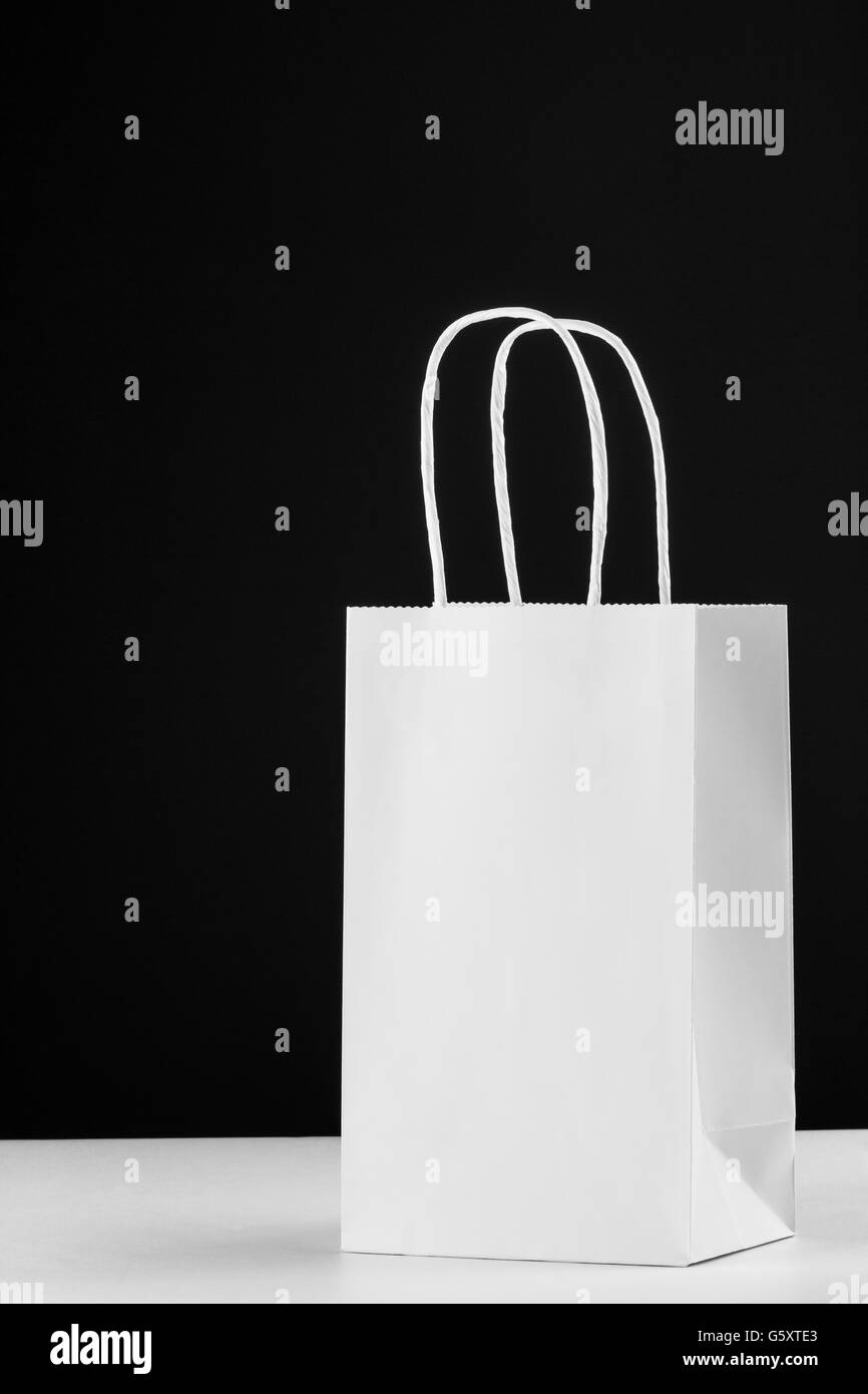 Plain blank white paper bag with handles on white counter with black ...