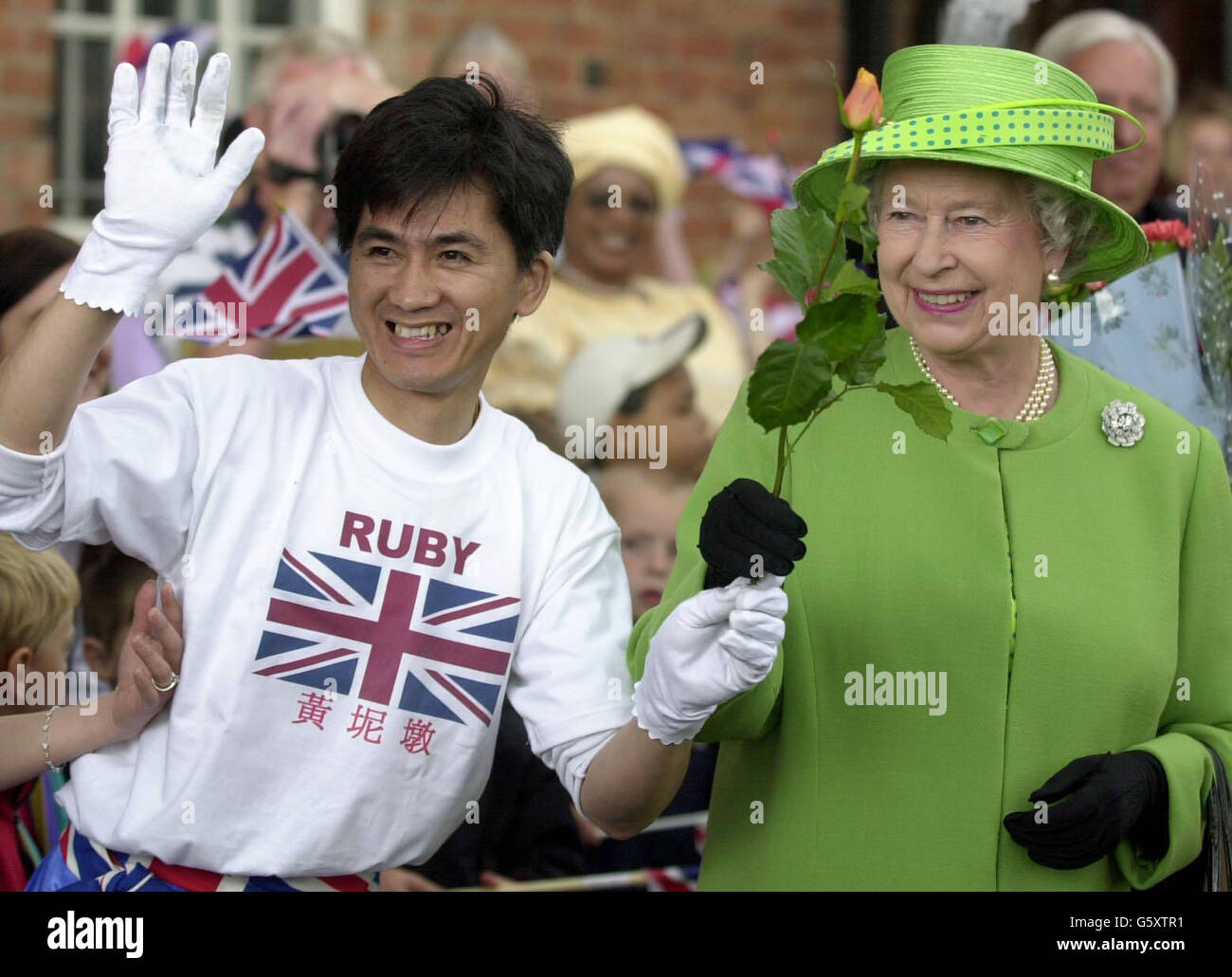 Britain's Queen Elizabeth II is presented with a rose by Simon Ho from ...