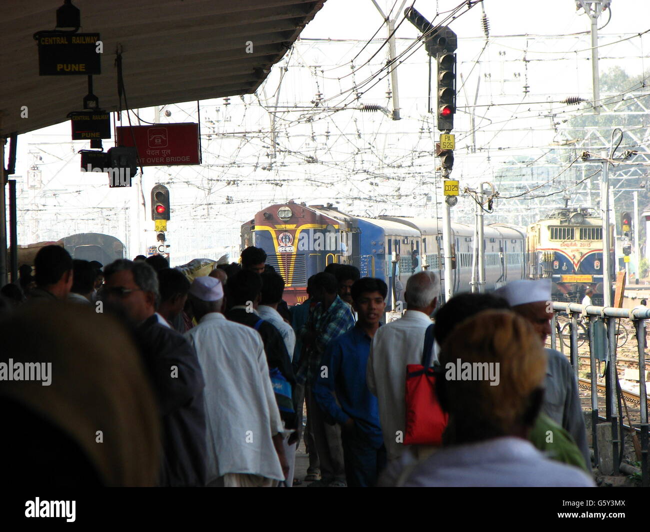 Passengers waiting for an arriving train at an Indian railway station ...
