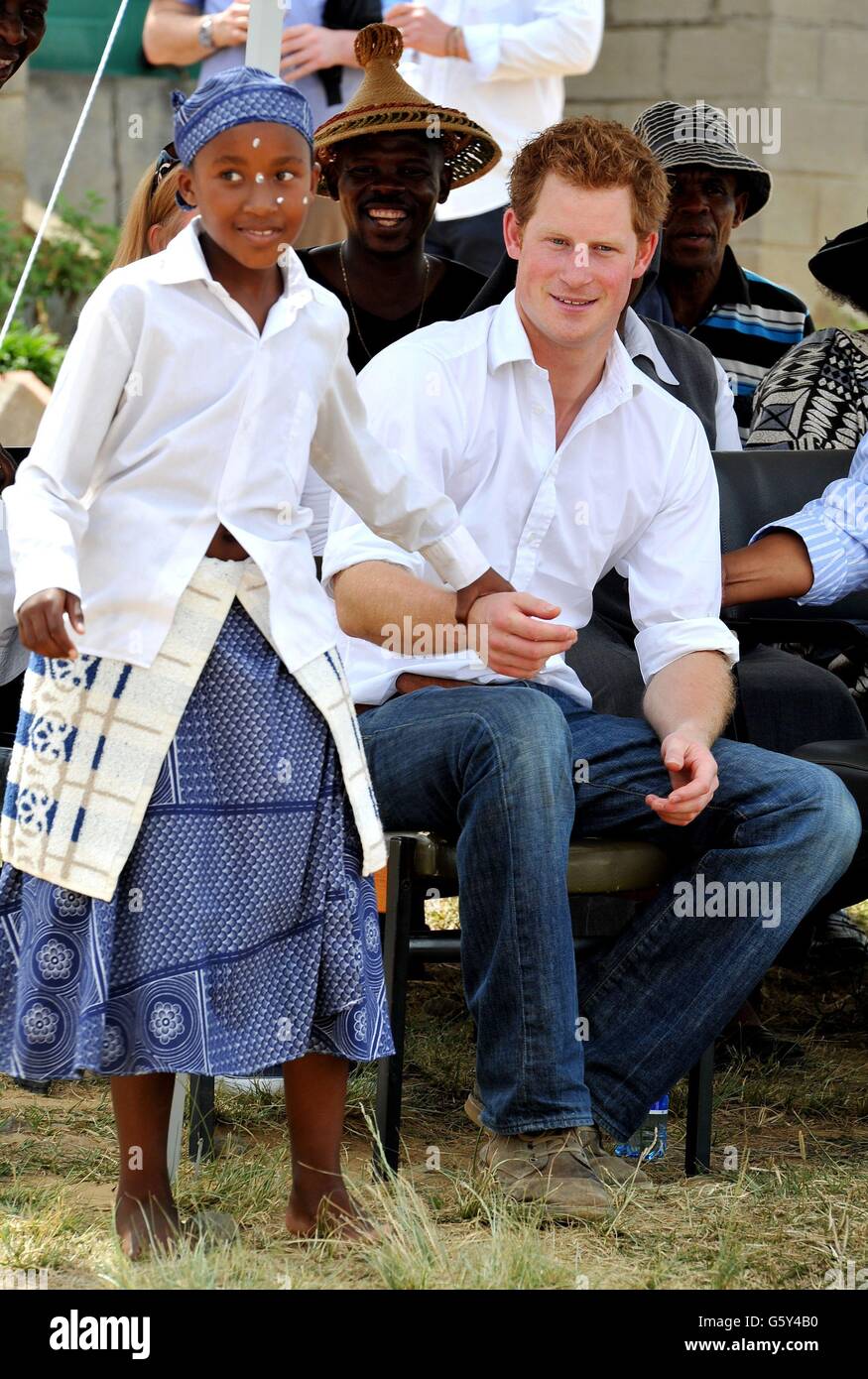 A young girl holds Prince Harry's hand as he is persuaded to join in ...