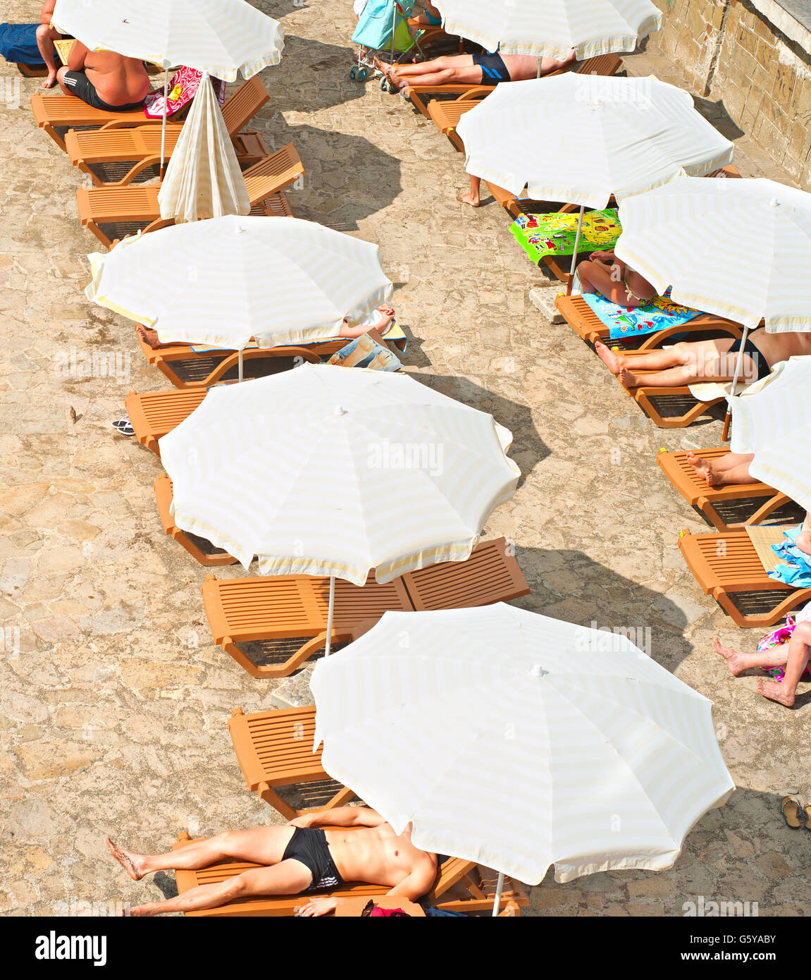 People at a sea beach under parasols taking sunbath Stock Photo - Alamy
