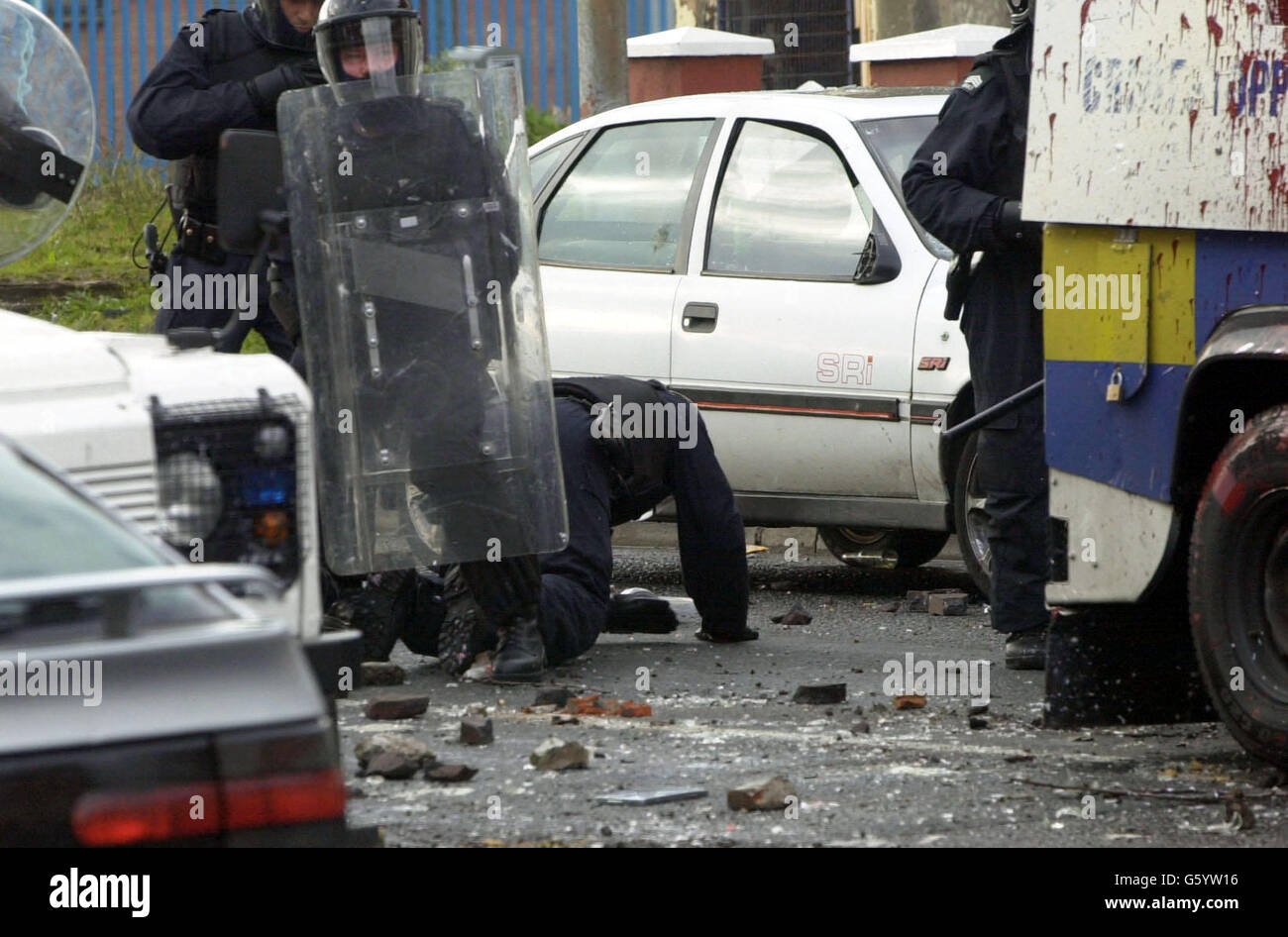 A Police Service of Northern Ireland officer falls down after being hit ...