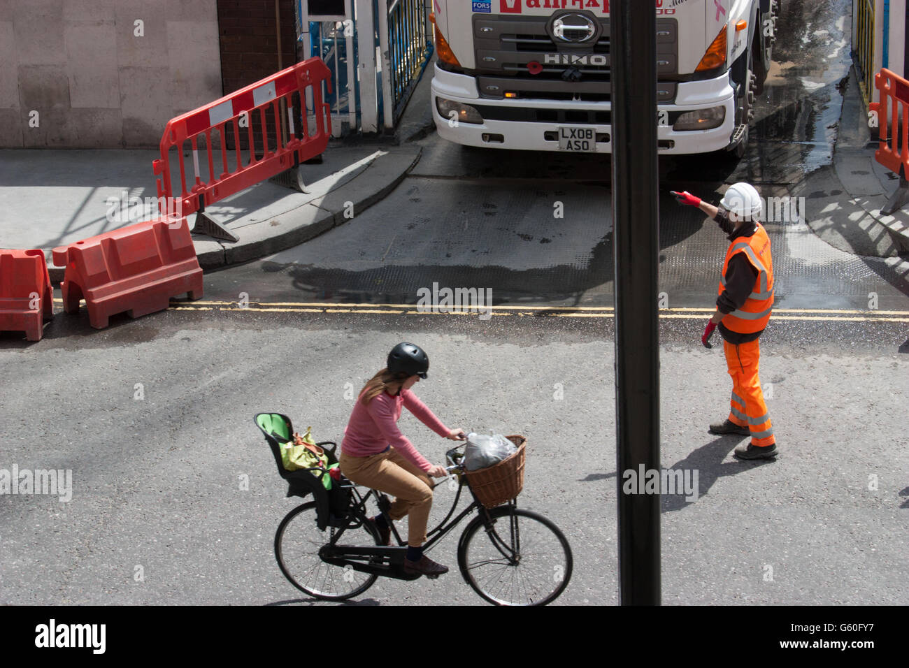 Female cyclist passing HGV heavy good vehicle Lorry in Central London ...