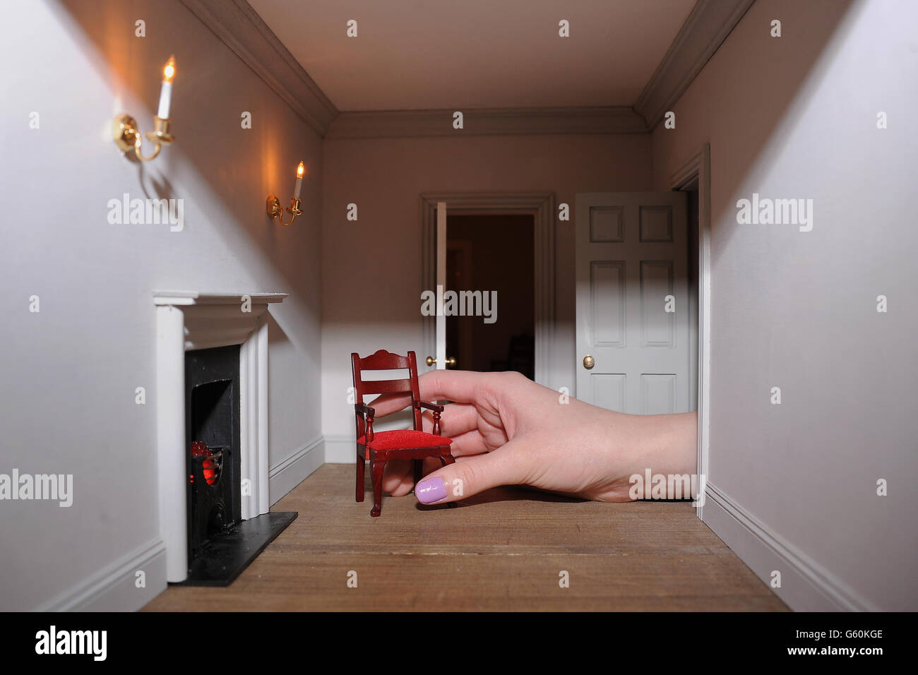 An exhibitor places a miniature chair into a dolls house during ...