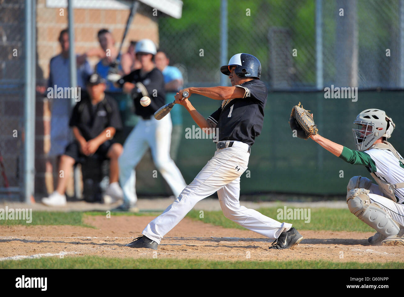 A high school batter making contact during a regular season varsity ...