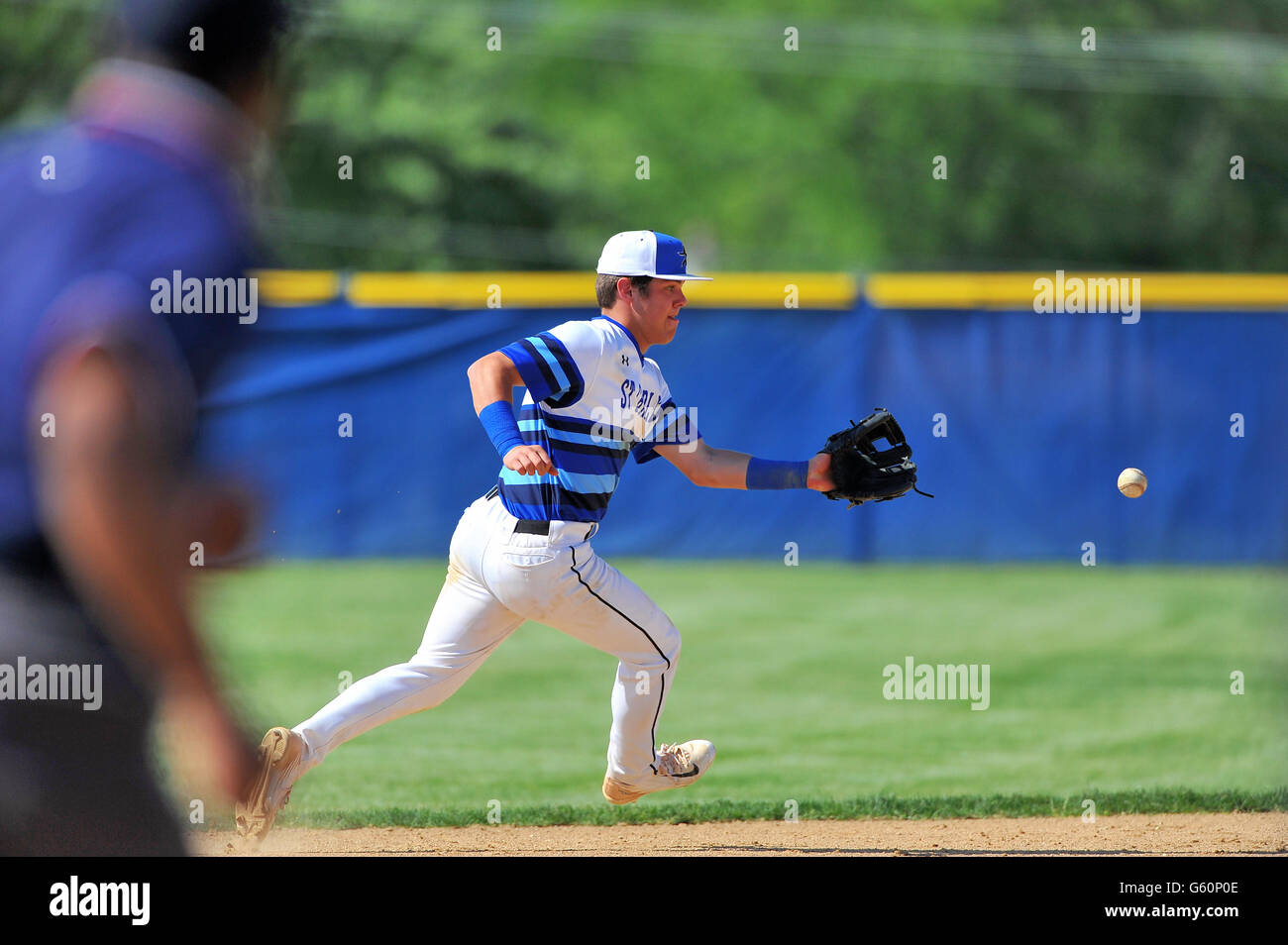High school shortstop sprinting to his left to snag a ground ball ...
