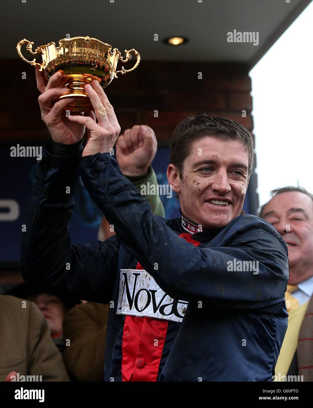 Jockey Barry Geraghty lifts the trophy after winning the Betfred ...