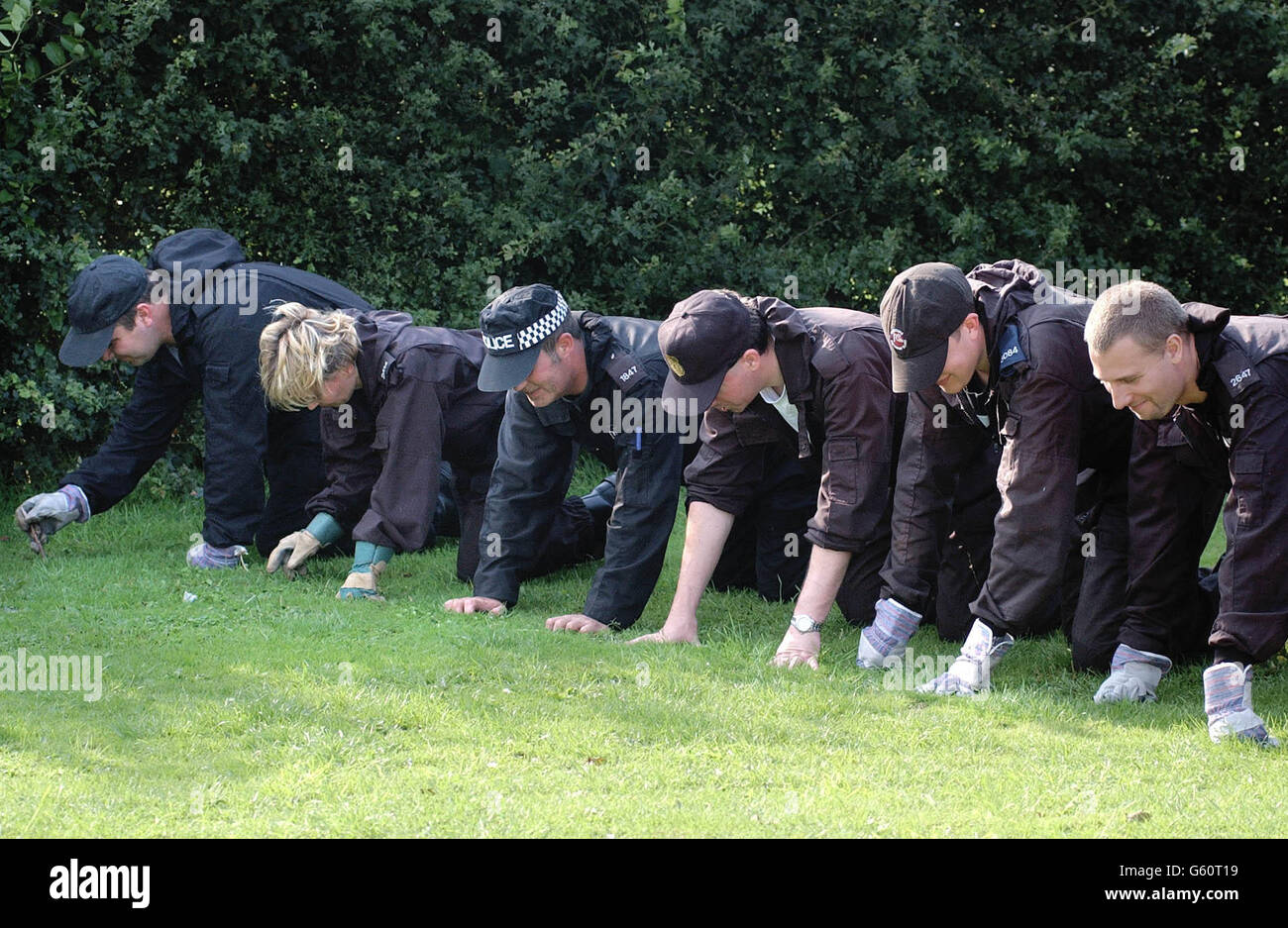 A Police search team carry out a fingertip search for clues about the ...