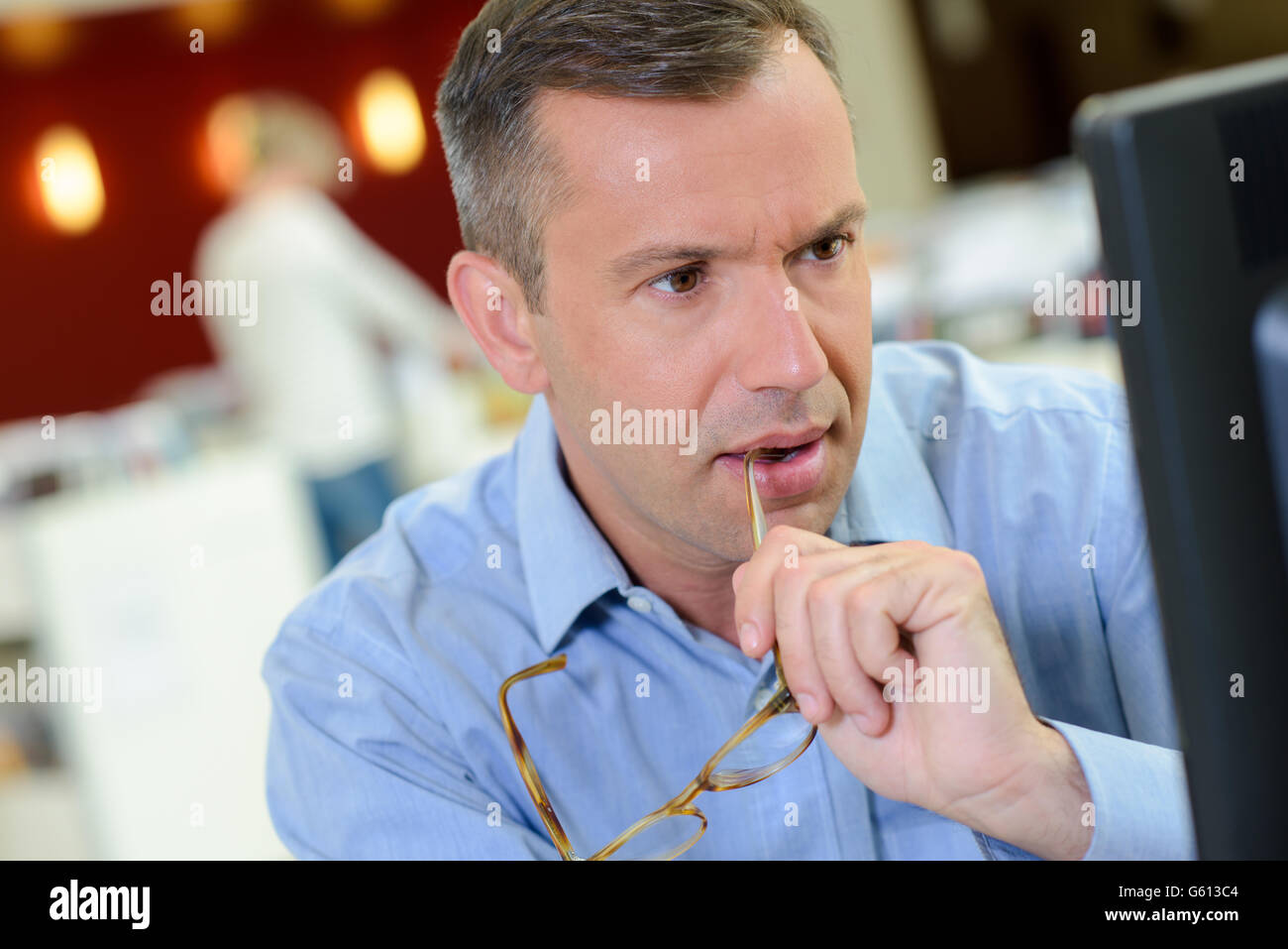 Man working on computer, arm of spectables in his mouth Stock Photo - Alamy