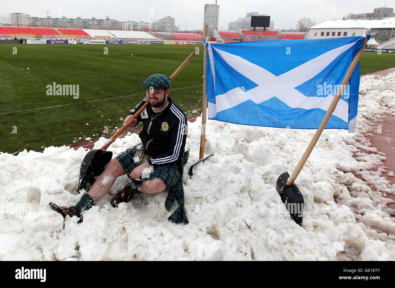 Scotland fan Dougie McKinlay (centre) helps clear snow from the pitch ...
