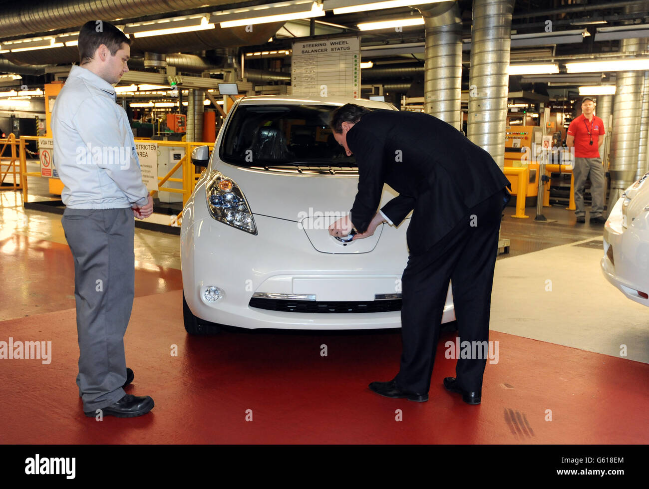 Prime Minister David Cameron attaches a Nissan badge to the front of a ...