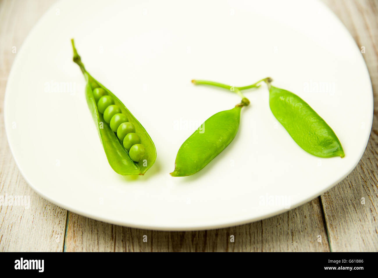 Green pea pods on the white plate Stock Photo - Alamy