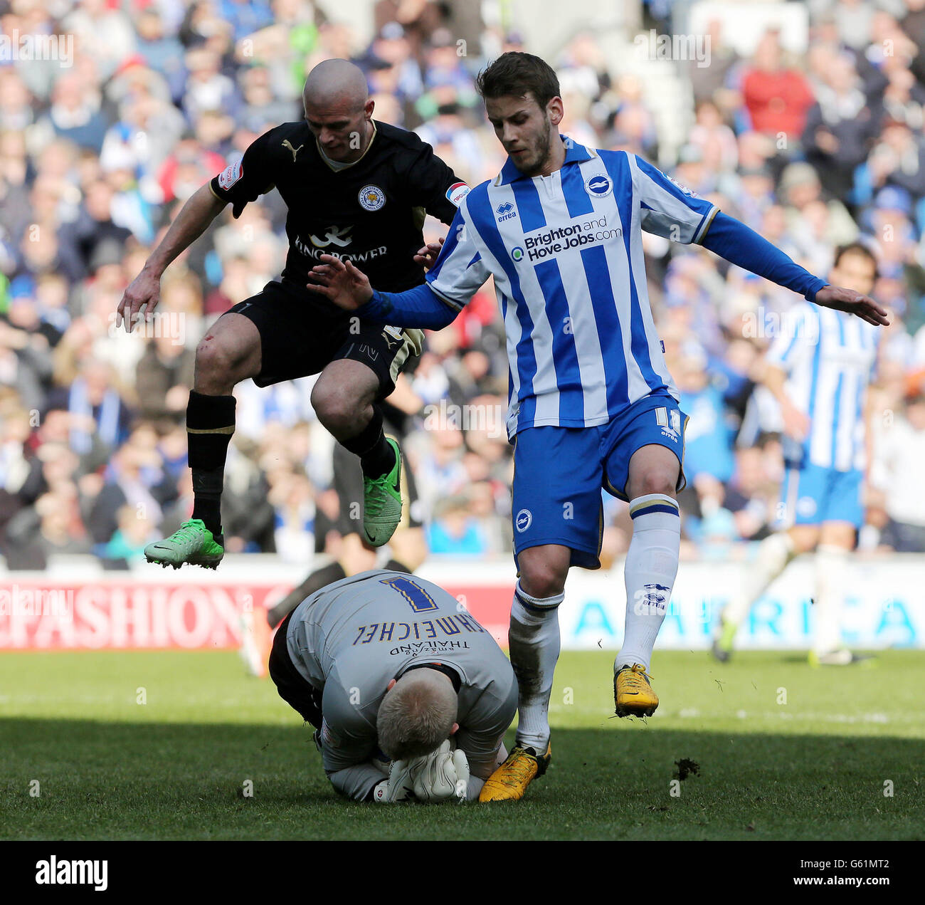 Leicester goal keeper Kasper Schmeichel dives at the feet of Brighton's ...