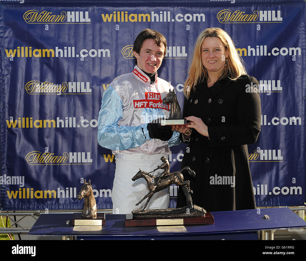 Jockey Benjamin Poste (left) is presented with a trophy after winning ...