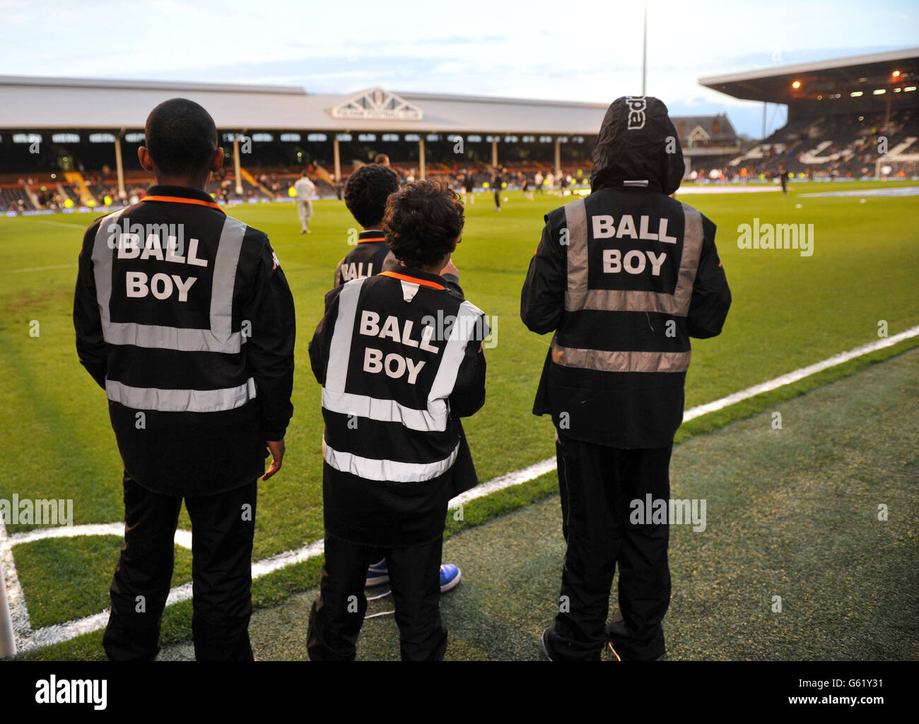 Ball boys watch the pre-match warm up from pitch side Stock Photo - Alamy