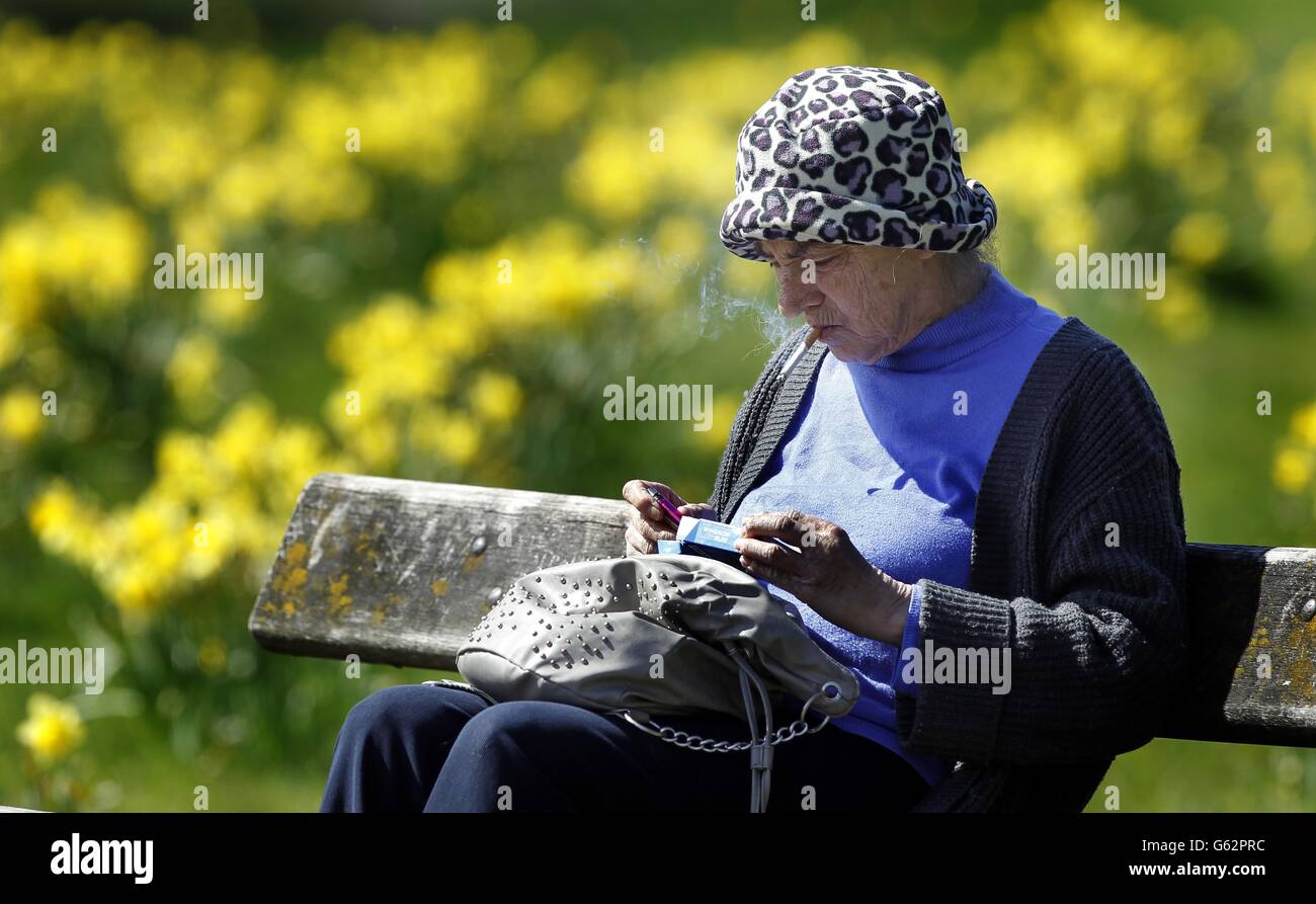 A lady sits on a bench in Sefton Park, Liverpool during the warm spring ...