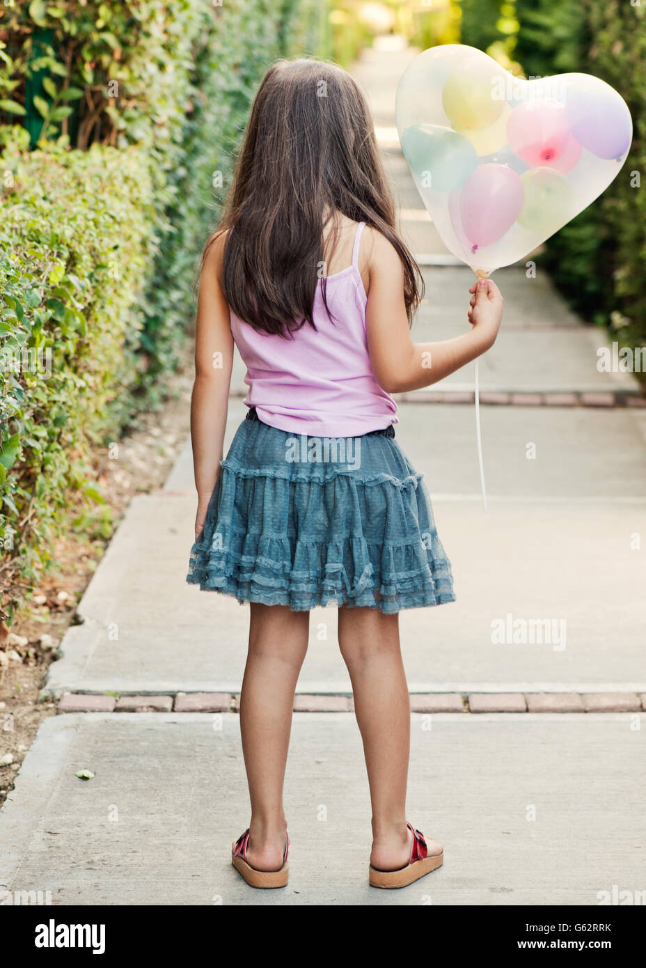 Rear view of child holding heart shape balloon Stock Photo - Alamy